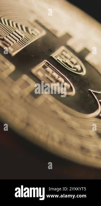 Vertical shot of golden bitcoin coin spinning on the black background ...