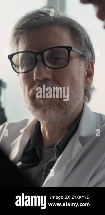Vertical shot of male and female scientists in lab coats conducting ...