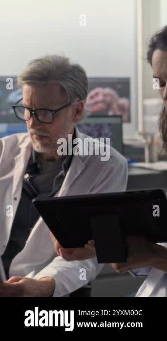 Two diverse scientists in lab coats discuss scientific research, look ...