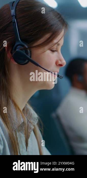 Vertical shot Portrait of Caucasian female technical support specialist in headset working on PC ...