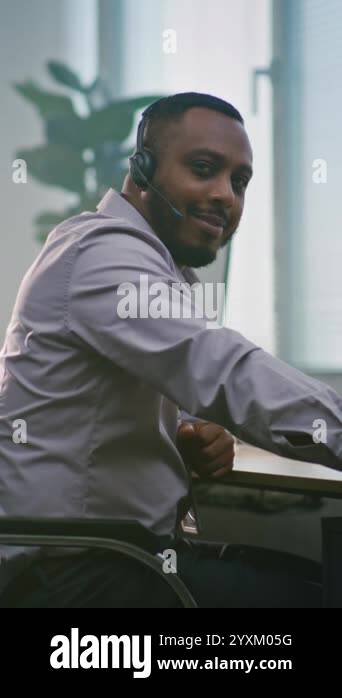 African American technical support operator in headset, sits in front ...