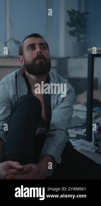 Vertical shot of stressed businessman sitting on the floor after fit of ...
