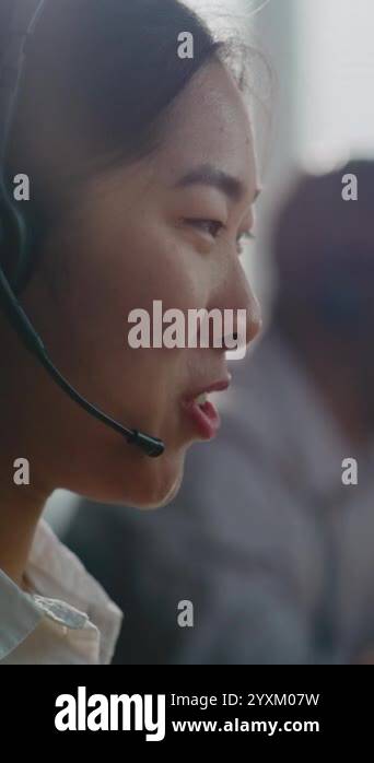 Vertical shot of Asian E-commerce manager in headset having conversation on call with customer ...