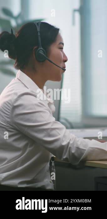 Multiethnic team of technical support operators working in modern call center office. Asian ...