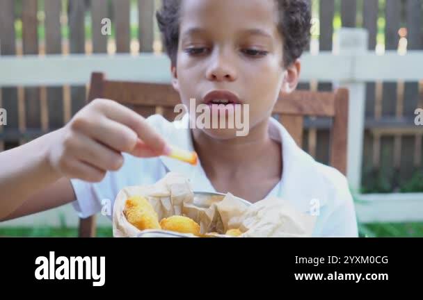 hungry african american teenager eats french fries with ketchup in park ...