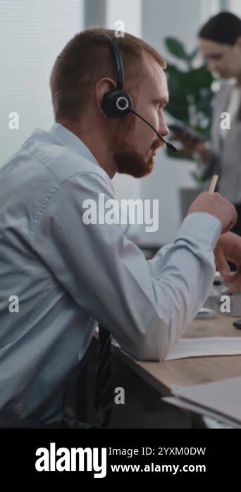 Vertical shot Male financial trader or stockbroker in headset works on ...