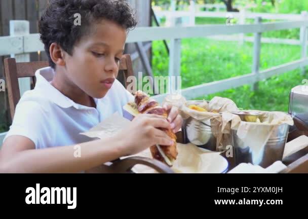 hungry african american teenager eats sweet croissant in park outdoors ...