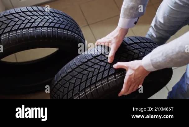Guy carefully checks strength of tire treads with hands. Man evaluates ...