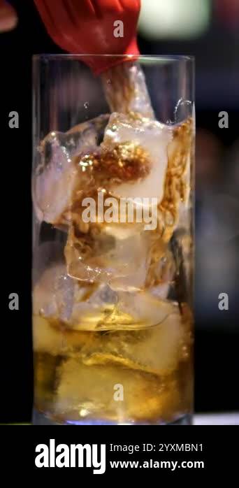 alcoholic cocktail with ice, dark rum, lime and coca cola. adding soda ...