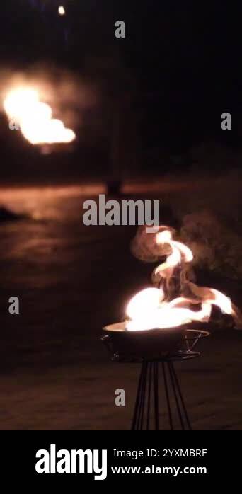 The man twists a long rope with a flame at the end and throws it far in ...