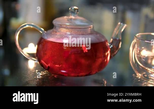 Cinemagraph slow motion shot of pouring hot tea from glass teapot into ...