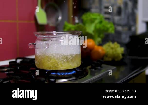 Water boiling in a pot over stove with pasta. Close up of boiling ...
