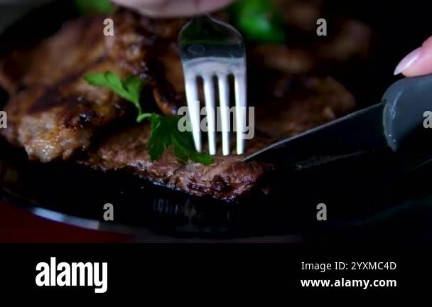 Chef slicing freshly grilled juicy beef steak meat with a knife on a ...