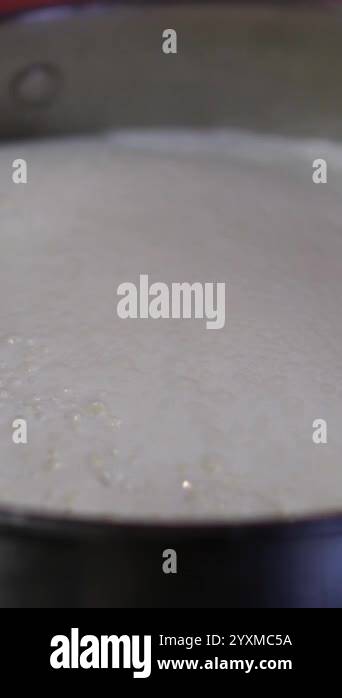 A pot of milk on a stovetop boils over, while steam escapes and milk ...