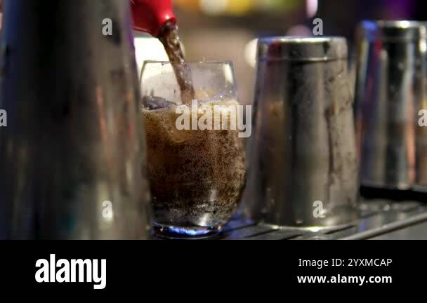 Pouring Cola with ice cubes close-up. Cola with Ice and bubbles in glass. Coke Soda closeup ...