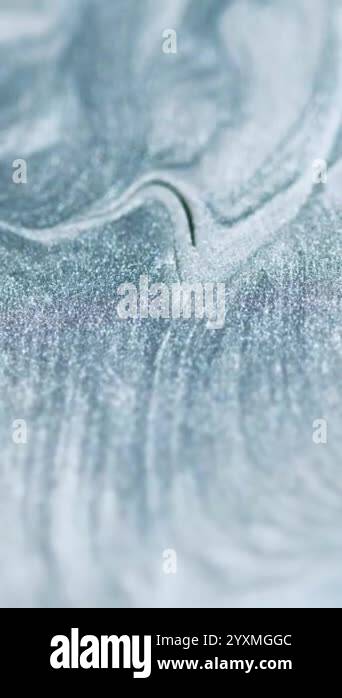 Vertical video. Glitter paint spill. Liquid silver texture. Defocused ...