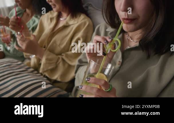 Tilt up slow motion of happy diverse gen Z women drinking refreshing ...