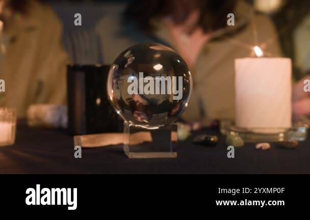 Focus on glowing crystal ball with reflection of unrecognizable women ...