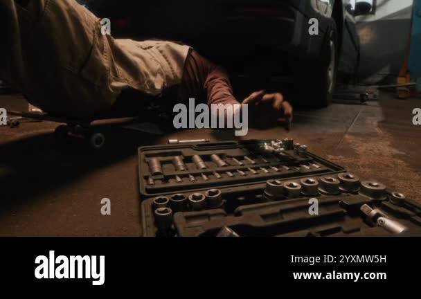 Young male mechanic in uniform inspecting breakdown cause and using ...