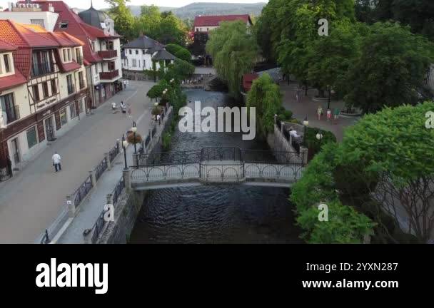 A drone flyover along a small river and promenade in the center of a ...