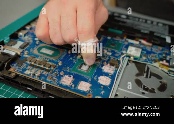 Repairman spreading thermal paste on laptop GPU during maintenance ...