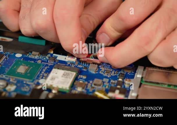 Engineer repairing notebook motherboard by adjusting cable connection ...