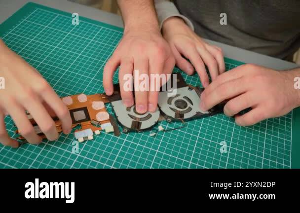 Father and son assembling laptop cooling system, aligning fans and heatsink components. Male and ...