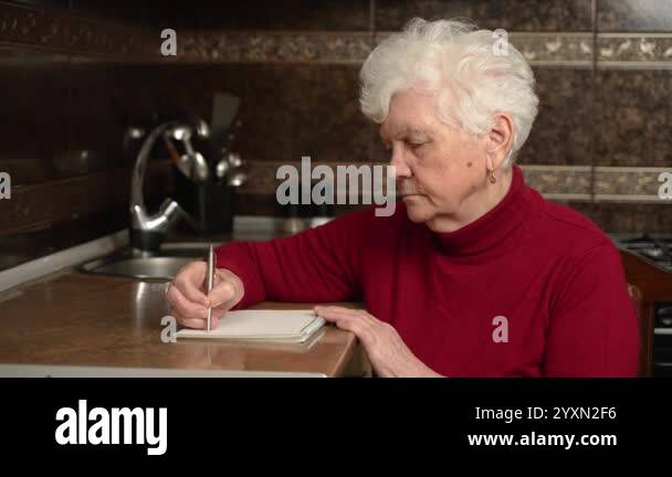 Old woman writes text in notebook with pen. Senior female writing ...