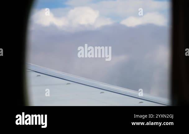 Aerial View Airplane Wing Soaring Through Fluffy Clouds in Clear Blue Sky During Daytime Travel ...