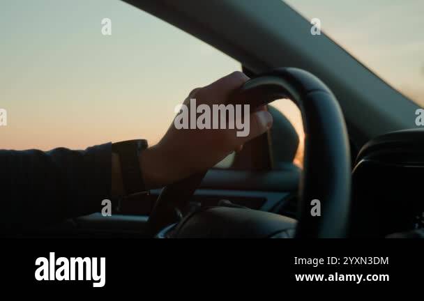 Close-up of hand on car steering wheel. Man driving car on highway at ...