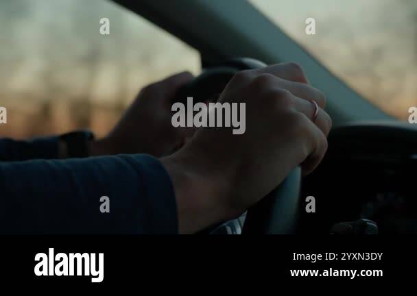 Close-up of hand on car steering wheel. Man driving car on highway at ...