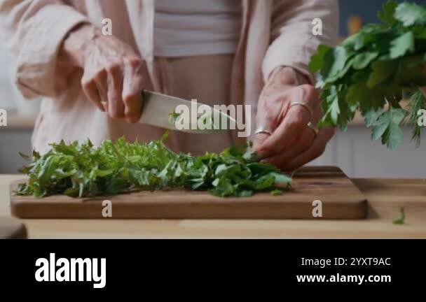 Closeup of unrecognizable female hands chopping fresh green herbs ...