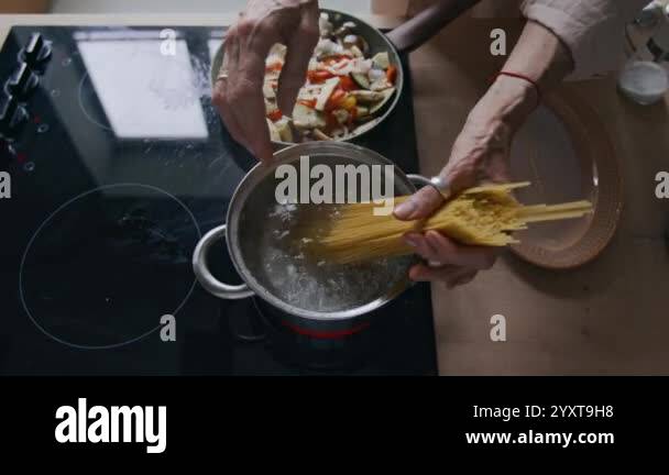 Top-down view shot of unrecognizable female chef putting spaghetti into ...