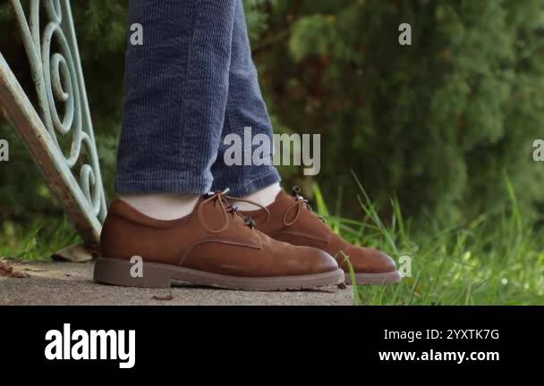 Close up of legs of a person in brown half-boots and corduroy trousers ...