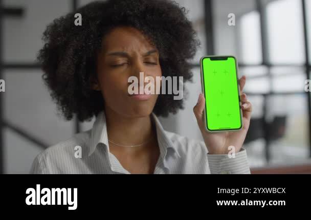 A woman shaking her head in disapproval, holding a smartphone with a ...