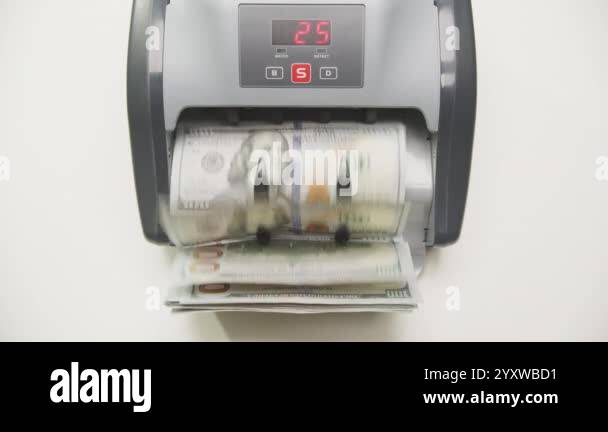 Money counting machine in operation, processing stacks of US dollar ...