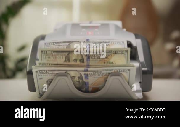 Hand adjusting a stack of US dollar bills in a money counting machine ...