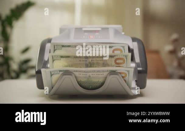 Dolly zoom shot of a money counting machine with stacks of US dollar bills, creating a dramatic ...