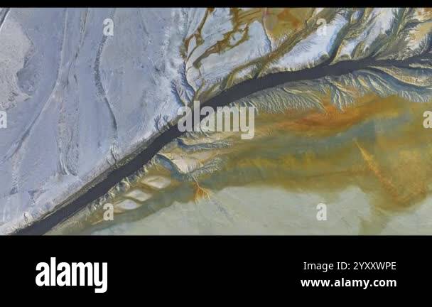 This video captures an aerial perspective of a river winding through a landscape, with intricate ...