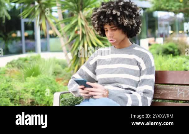 A mixed race girl with vitiligo relaxes on a university campus bench ...