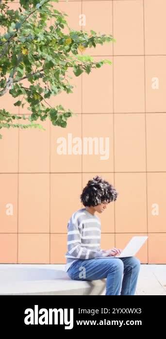 A mixed race girl with vitiligo relaxes at a university campus ...