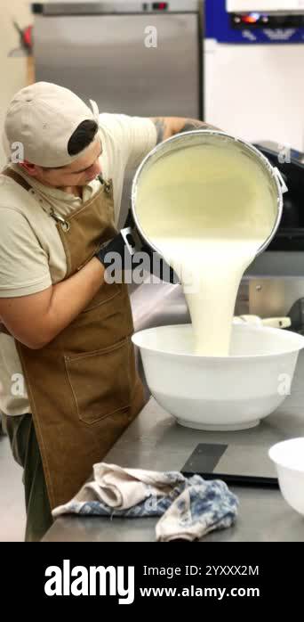 A pastry chef carefully pours a creamy batter into a mixing bowl The ...