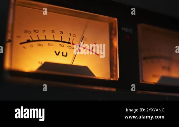 Close-up of a vintage VU meter glowing with warm amber light ...