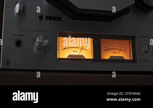 Front panel of a classic analog tape recorder with glowing VU meters ...
