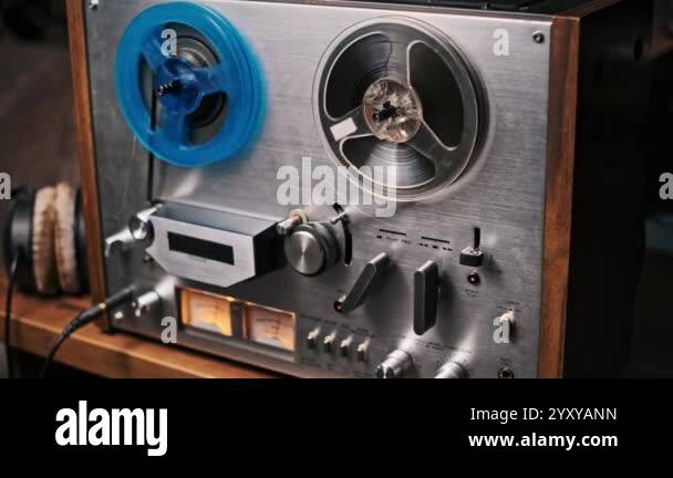 A male hand engages the playback lever on a vintage reel-to-reel ...
