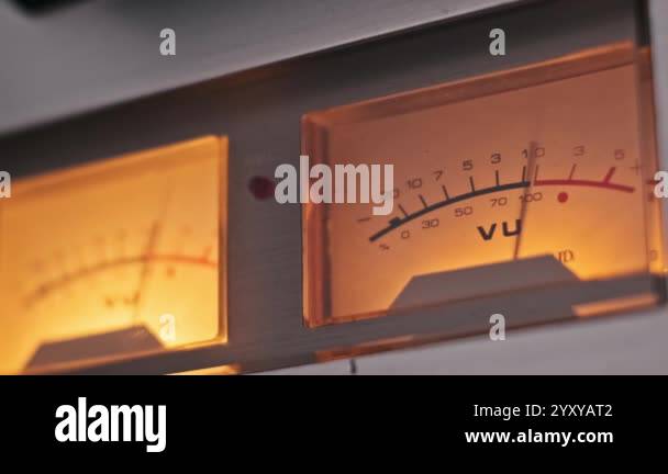 A close-up view of a glowing vintage VU meter on an audio device ...