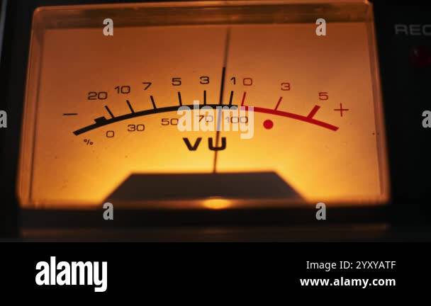 Close-up of vintage VU meter with needle fluctuating, illuminated by ...