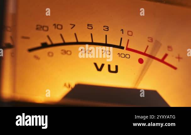 A detailed shot of a vintage analog VU meter with a red needle near the ...