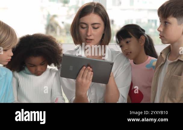 Smart teacher holding tablet while open online lesson to group of ...