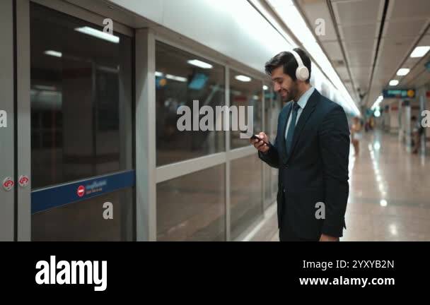 Project manager wearing headphone at train station while holding mobile ...